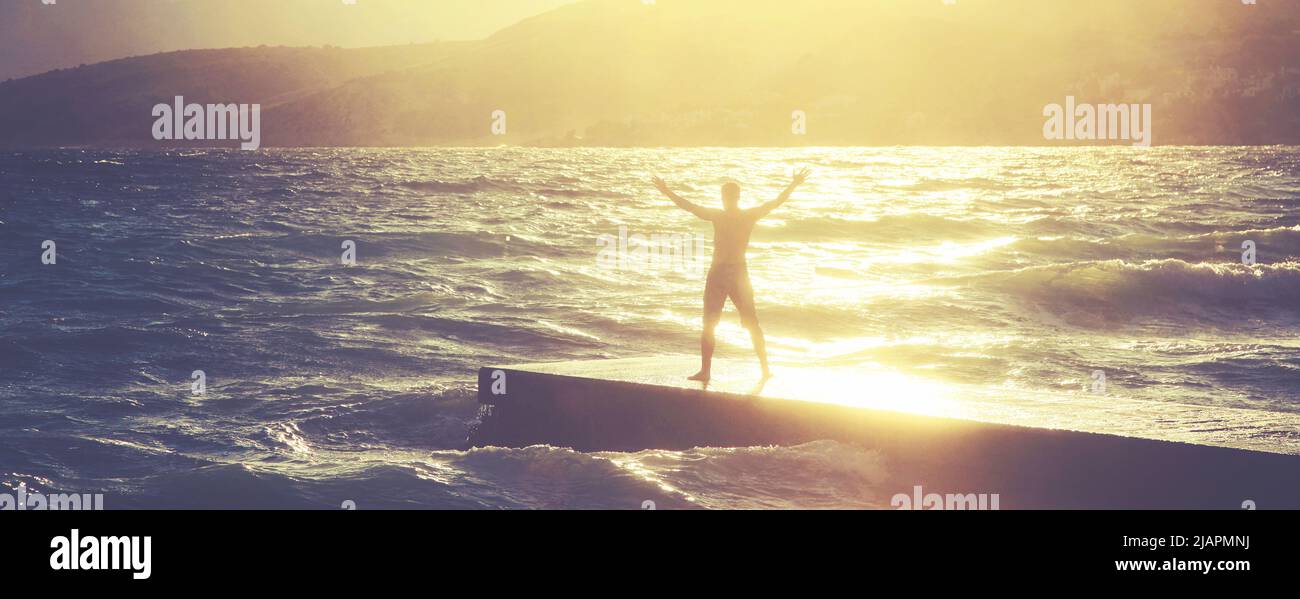 Feeling of freedom concept. Man standing on pier facing to the sea with ...