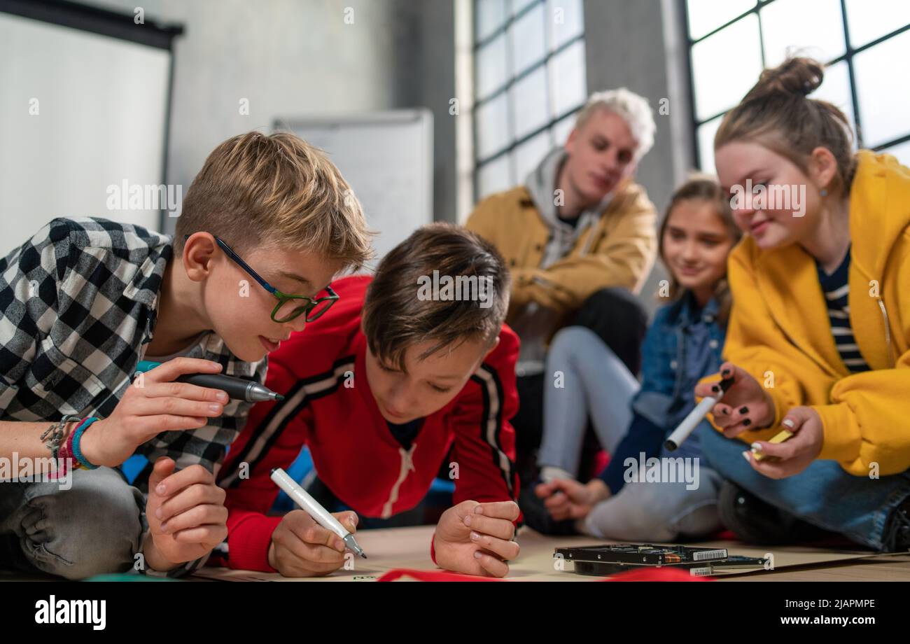 Group of happy kids with their teacher working on project together at ...