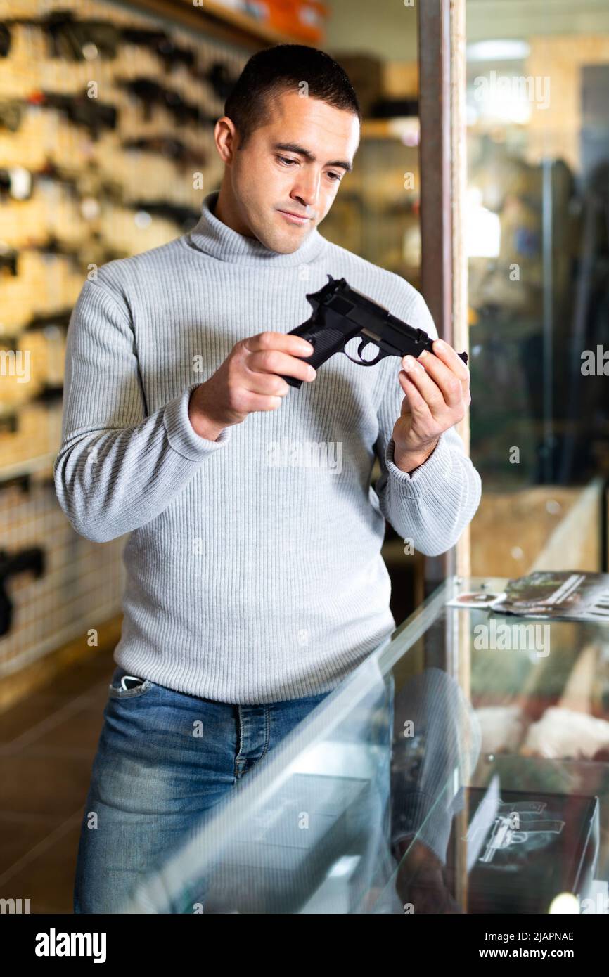 Male shopper carefully selects pistol at gun store Stock Photo - Alamy