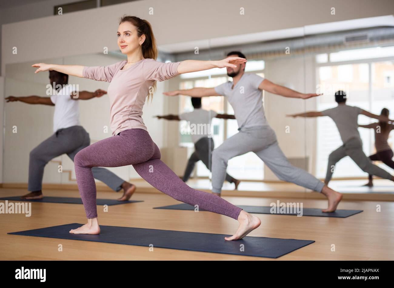 Young woman standing in Revolved High Lunge Pose during yoga class ...