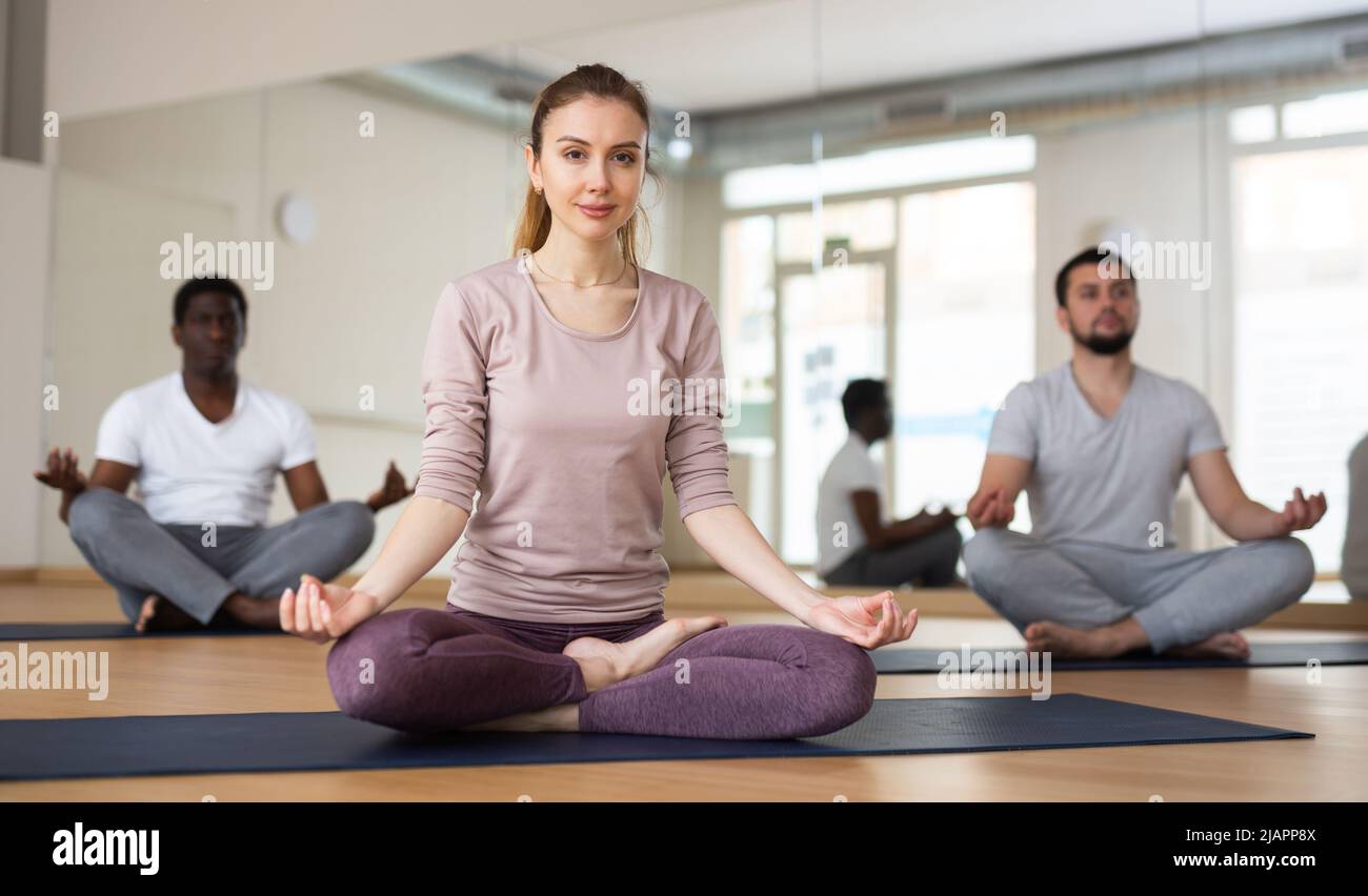 Woman sitting in lotus position with hands on knees folded in mudra ...
