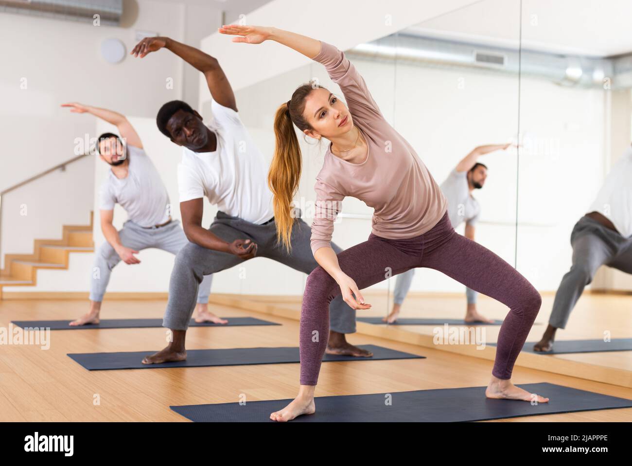 Woman performing stretching during group yoga training Stock Photo - Alamy
