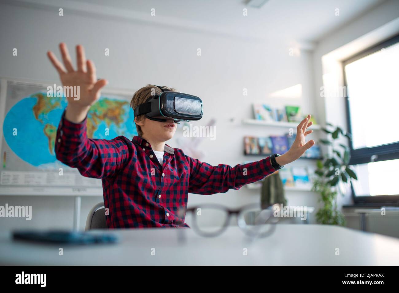Curious student wearing virtual reality goggles at school in computer ...