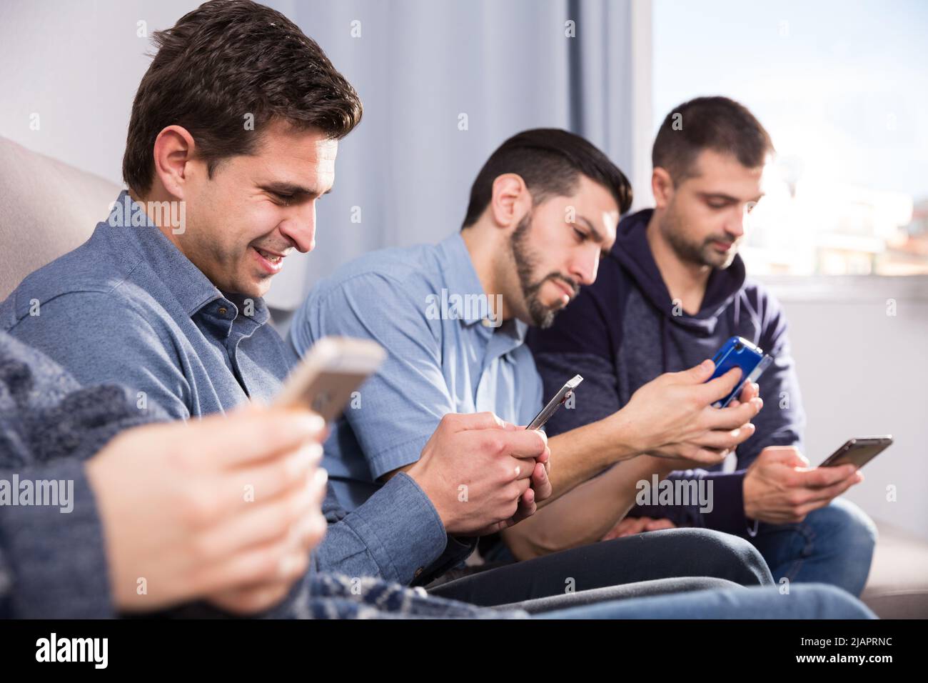 Males with phones on sofa Stock Photo - Alamy