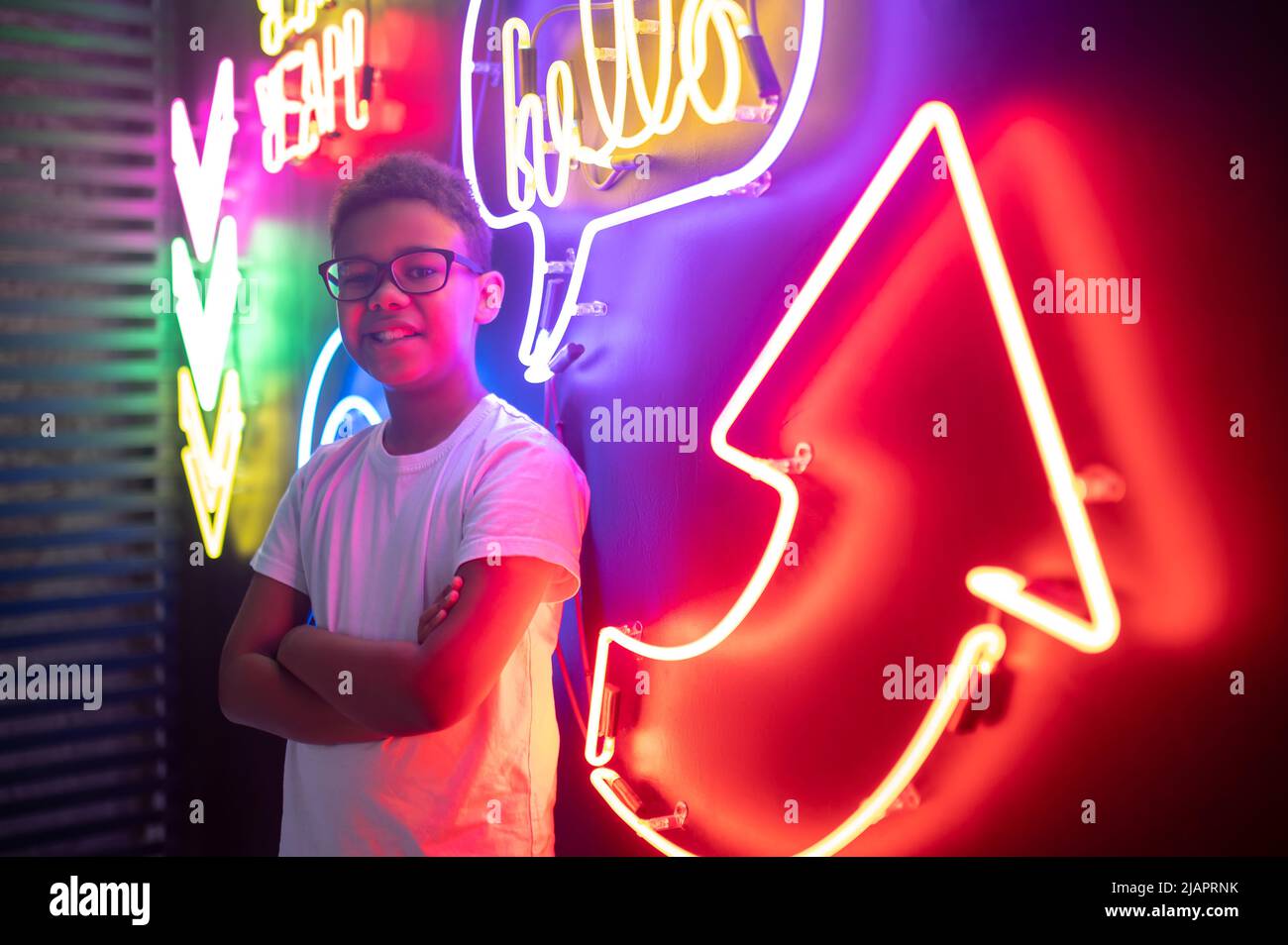 Adolescent standing alone by a wall with neon signs Stock Photo - Alamy