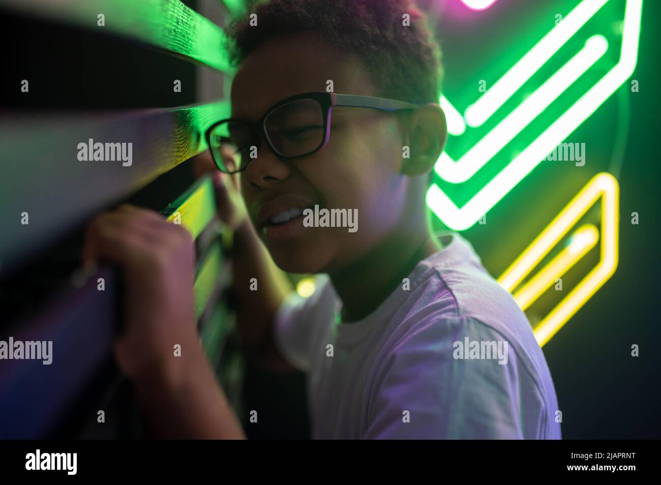 Teenager watching something in a room with neon lighting Stock Photo ...