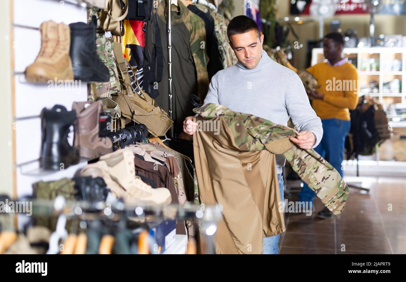 Man chooses camouflage uniform at army store Stock Photo - Alamy