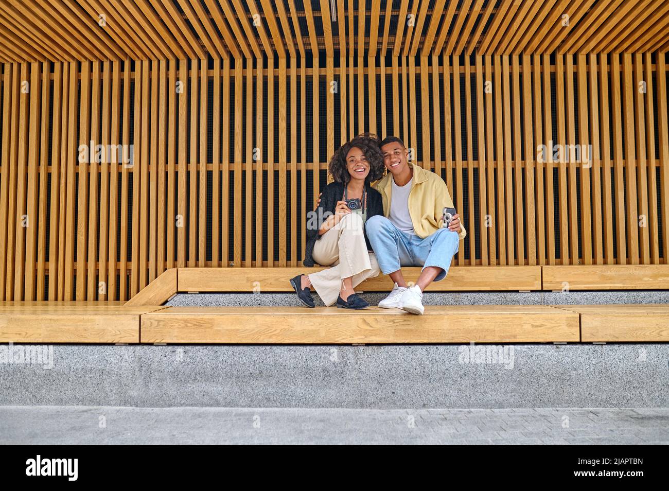 Guy hugging girl smiling at camera sitting outdoors Stock Photo - Alamy