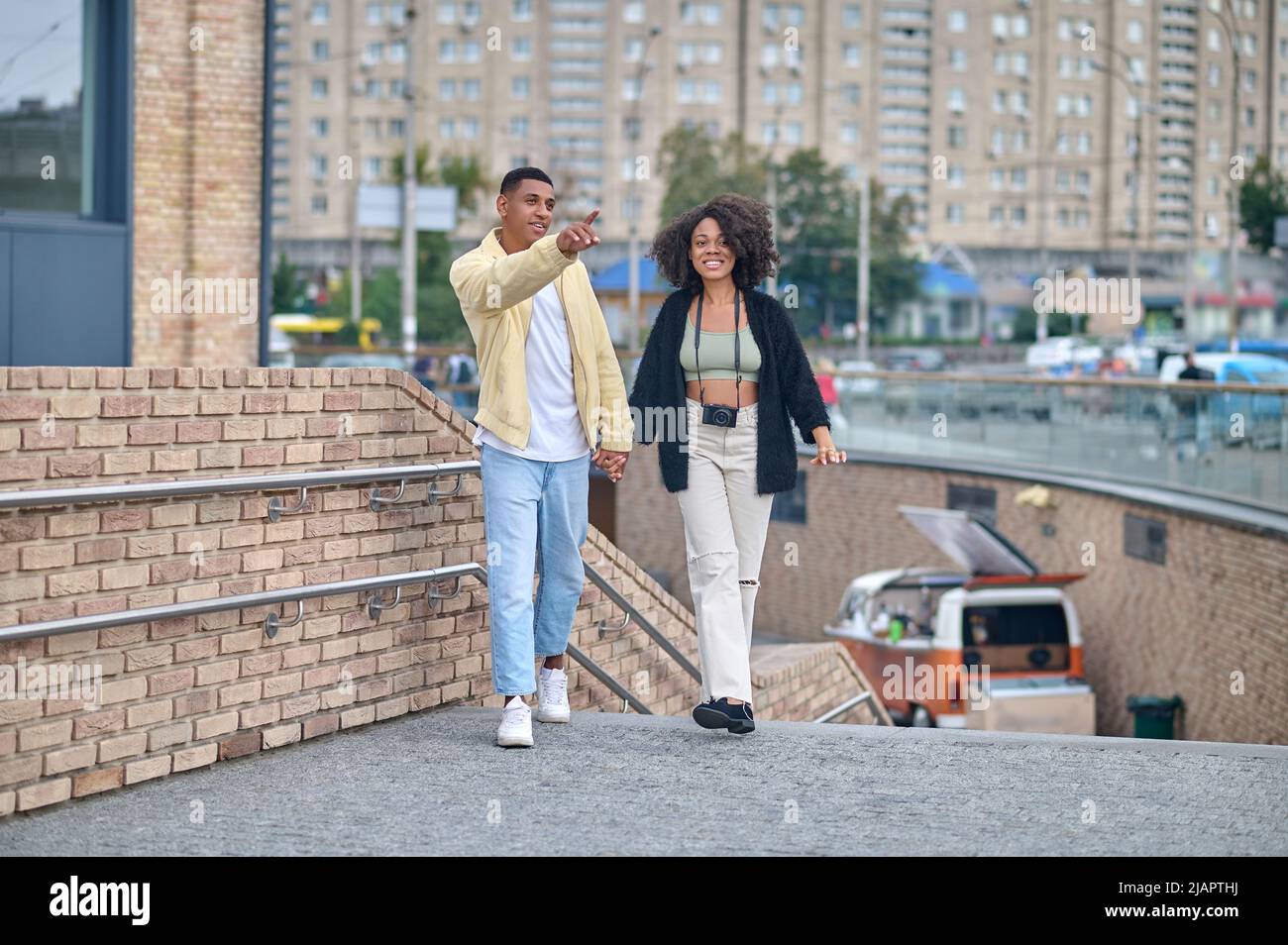 Guy pointing hand to side walking with girl Stock Photo - Alamy