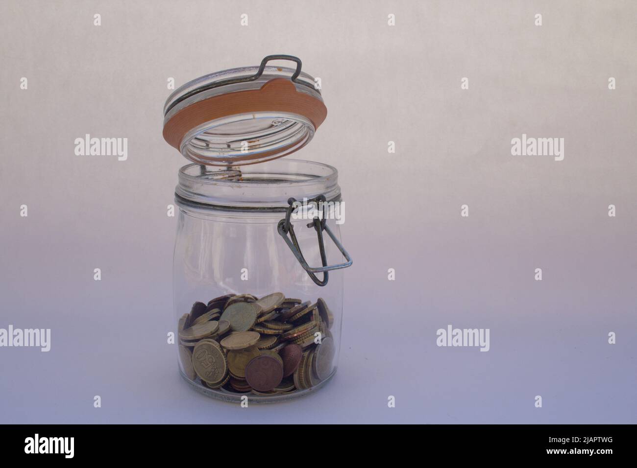 Image of a glass jar with padlock containing coins on a white ...