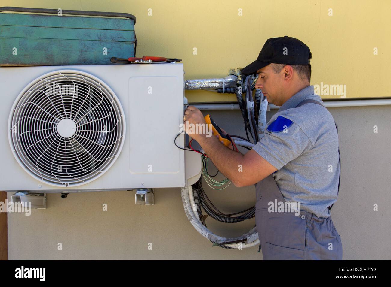Image of a plumber with tools and a tester who checks the current after ...