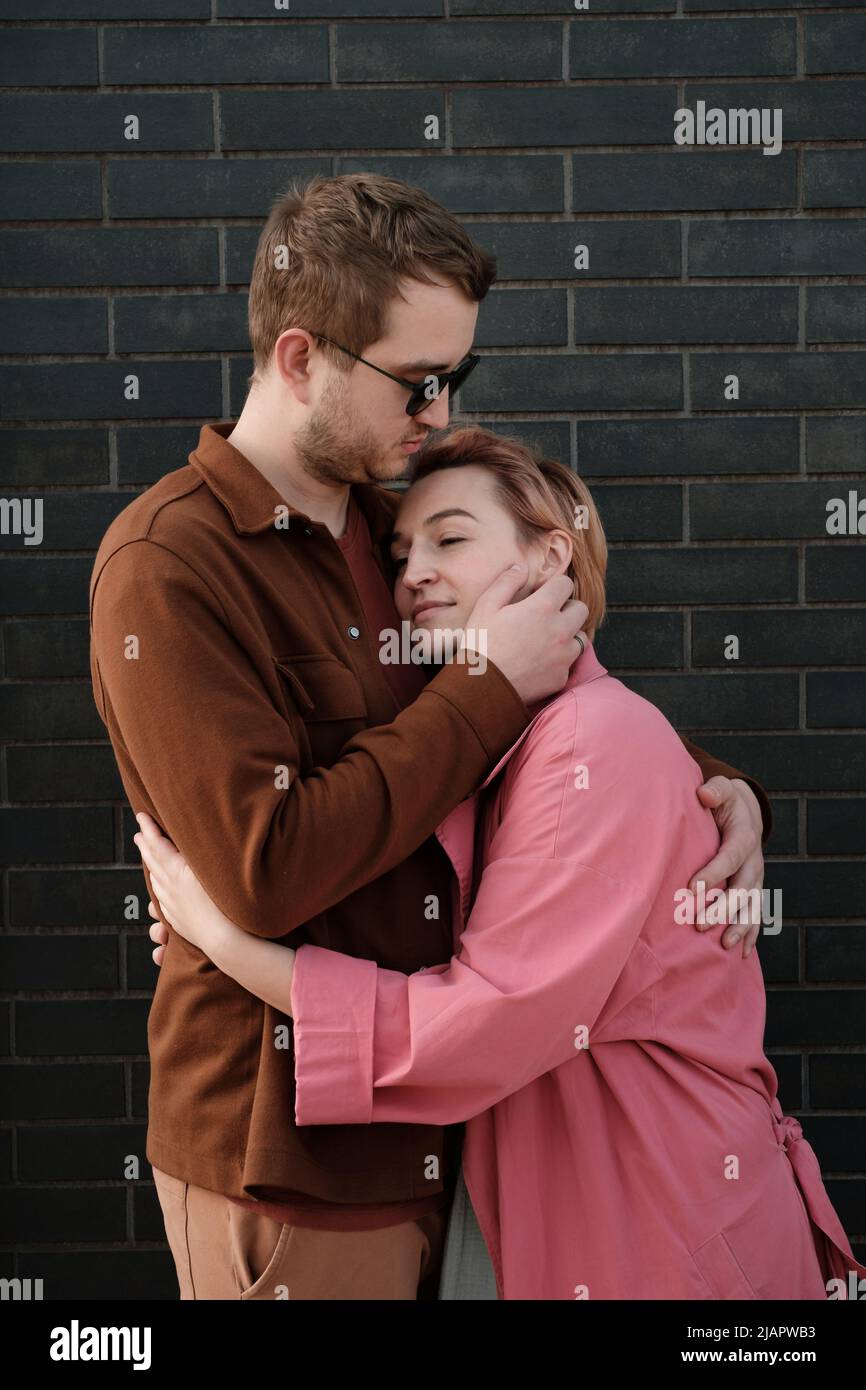 Couple hugging over dark wall. Happy man and woman touching tender each ...