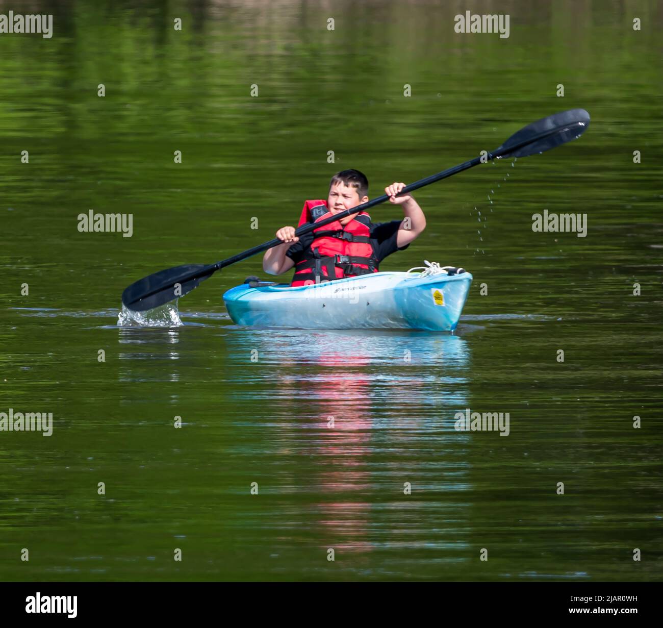 A boy paddling a kayak on the Allegheny River in Althom, Pennsylvania ...