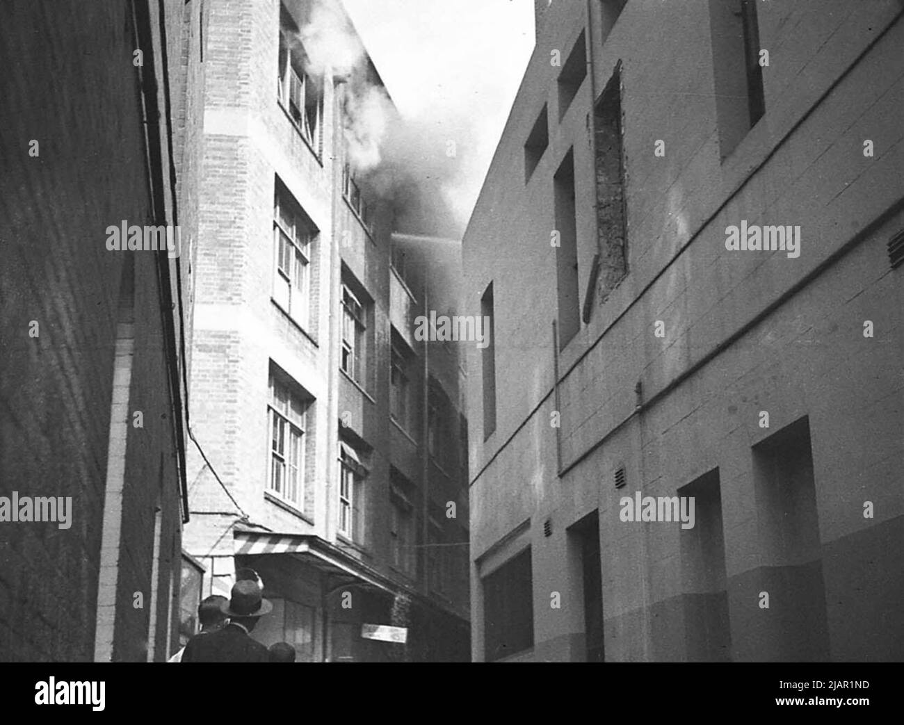 People watch as firefighters put out a fire in a high rise building in ...