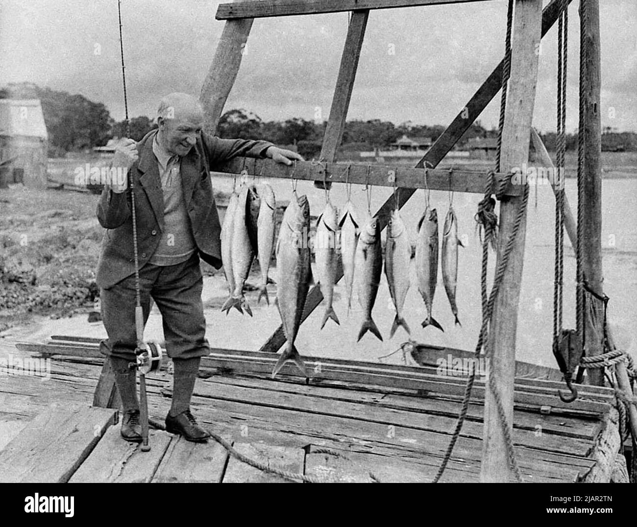 Old man with fishing rod displaying his catch of fish ca. 1937 Stock ...