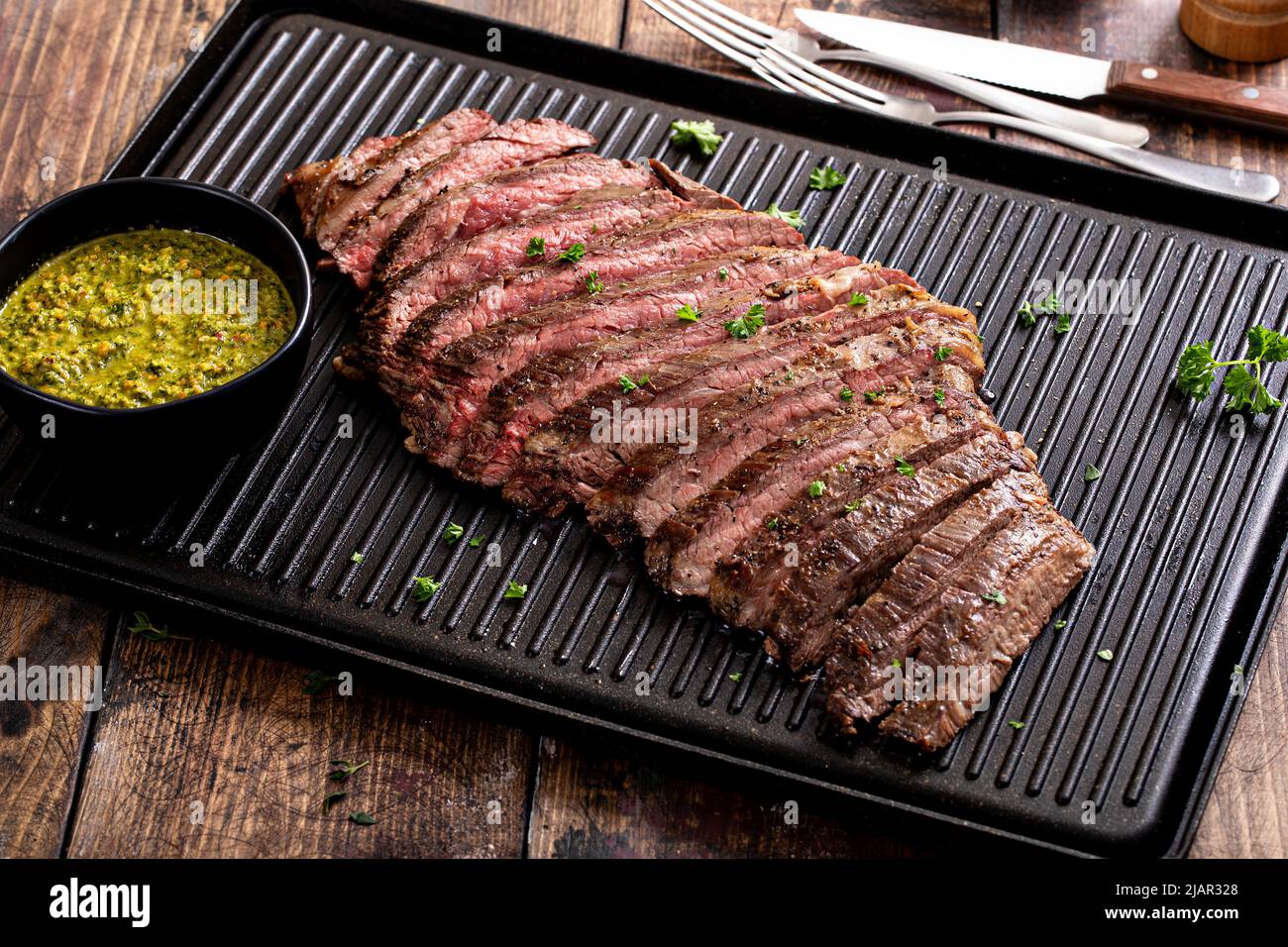 Grilled flank steak with chimichurri sauce on a grill pan Stock Photo ...