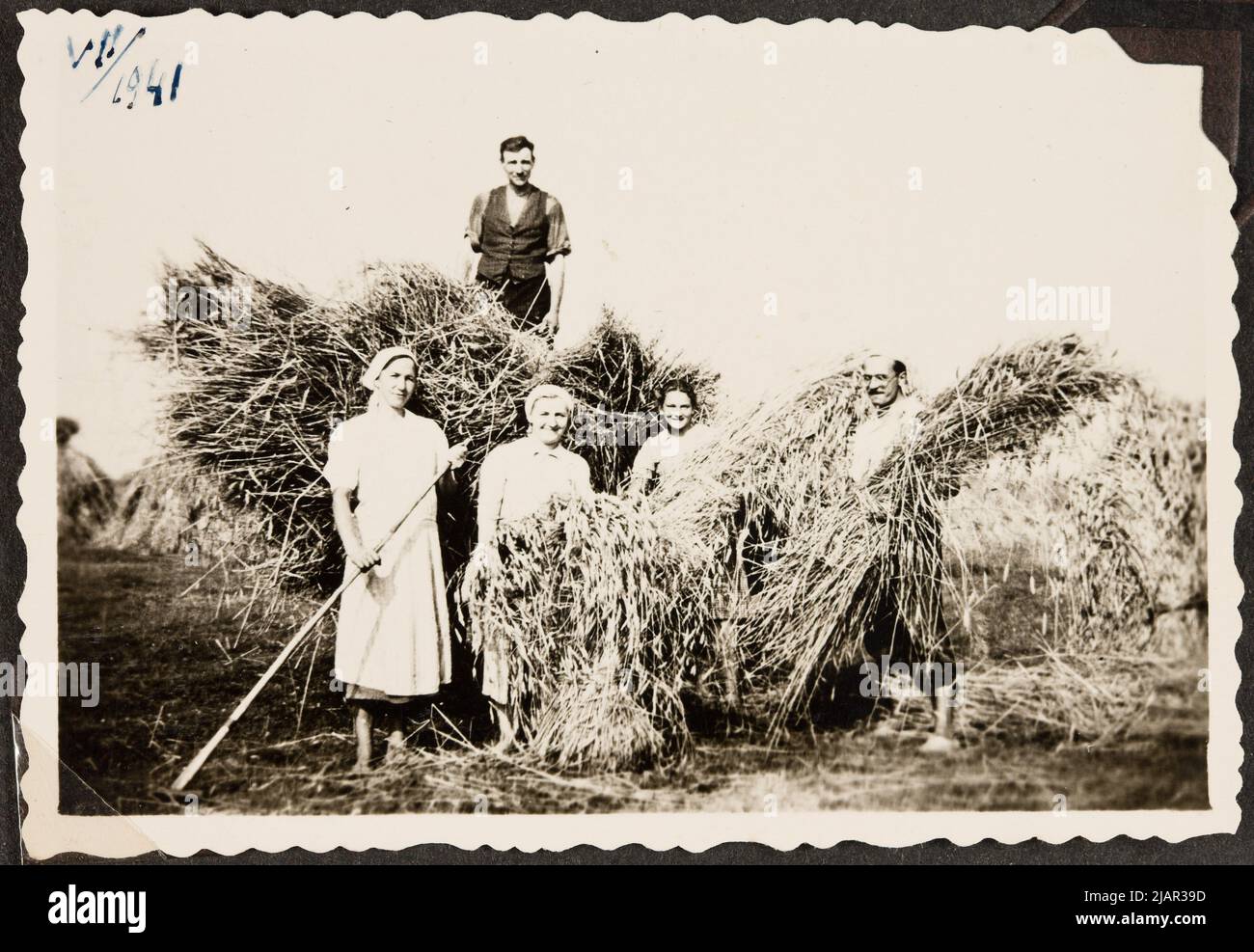 A group of people standing against the background of a wagon with hay a ...