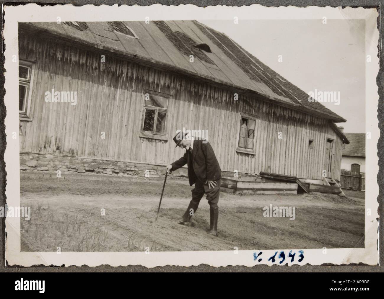 Stachiewicz Roman Senior supported by a cane in front of a long wooden ...