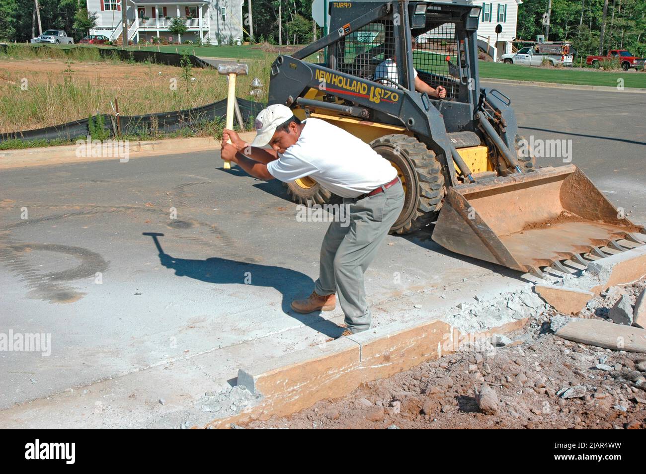using Bobcat and hand sledge sledgehammers to level and clean dirt site ...