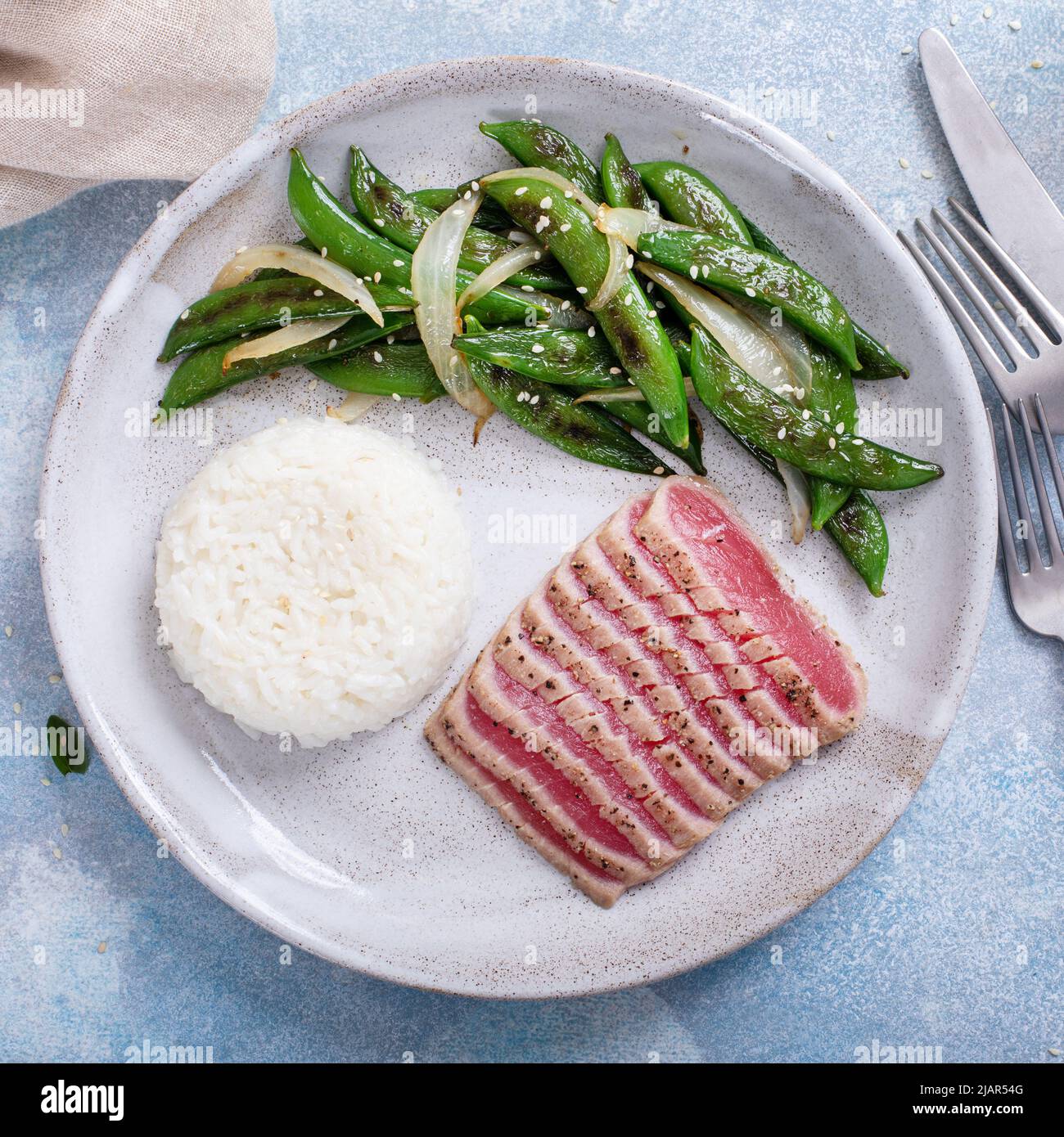 Seared tuna steak with white rice and green peas Stock Photo - Alamy