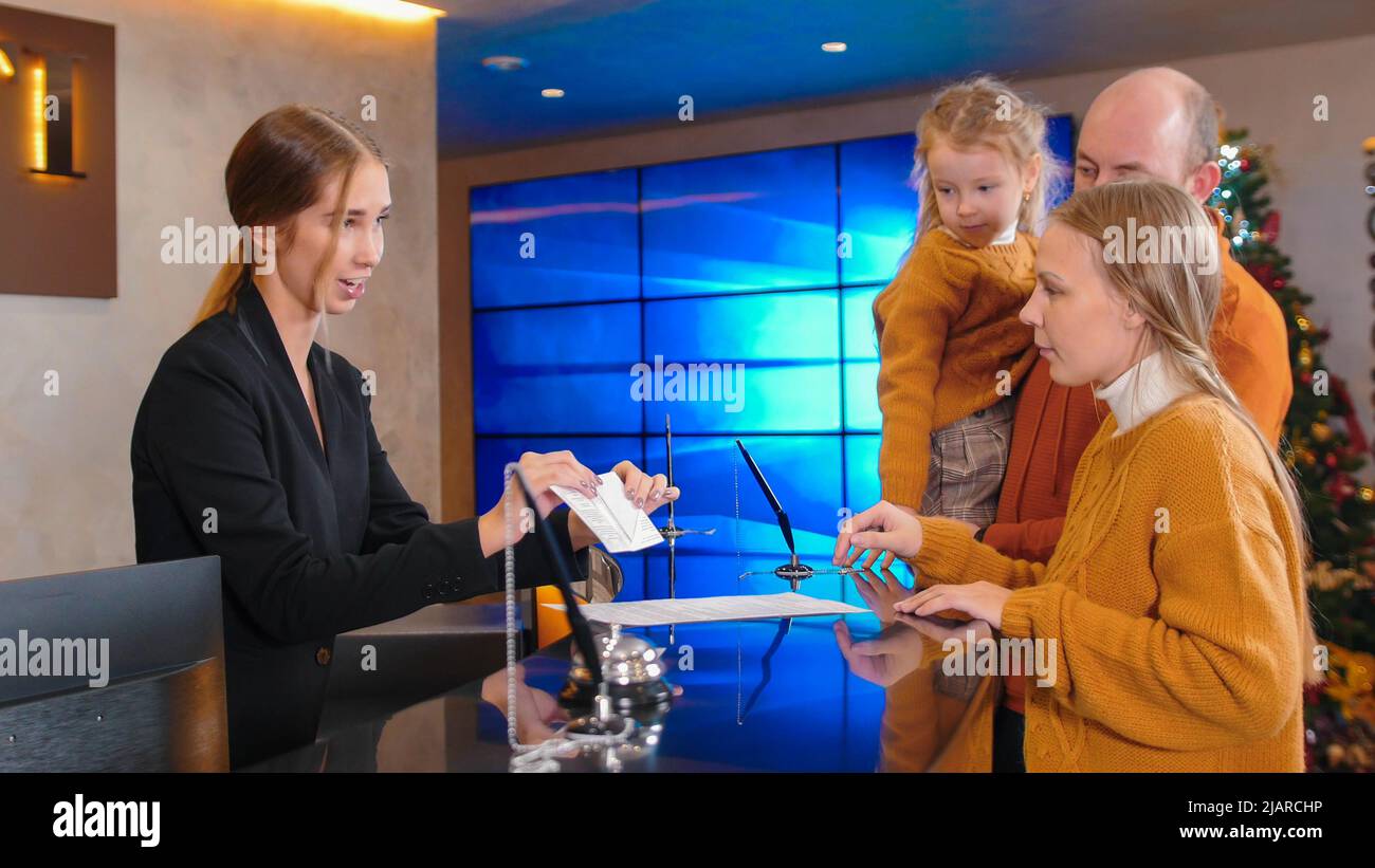 A family checking in the hotel room - a woman on the reception ...