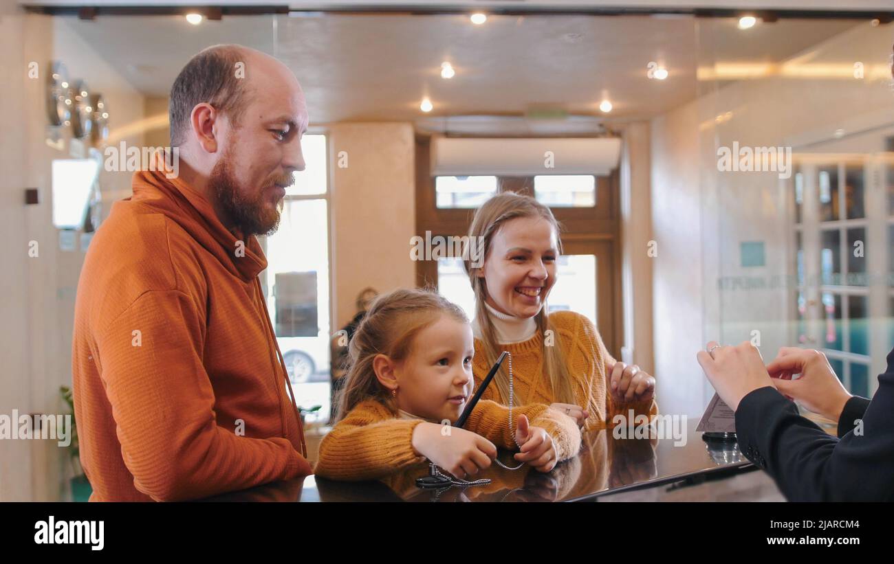 A smiling family checking in the hotel - standing by the reception ...
