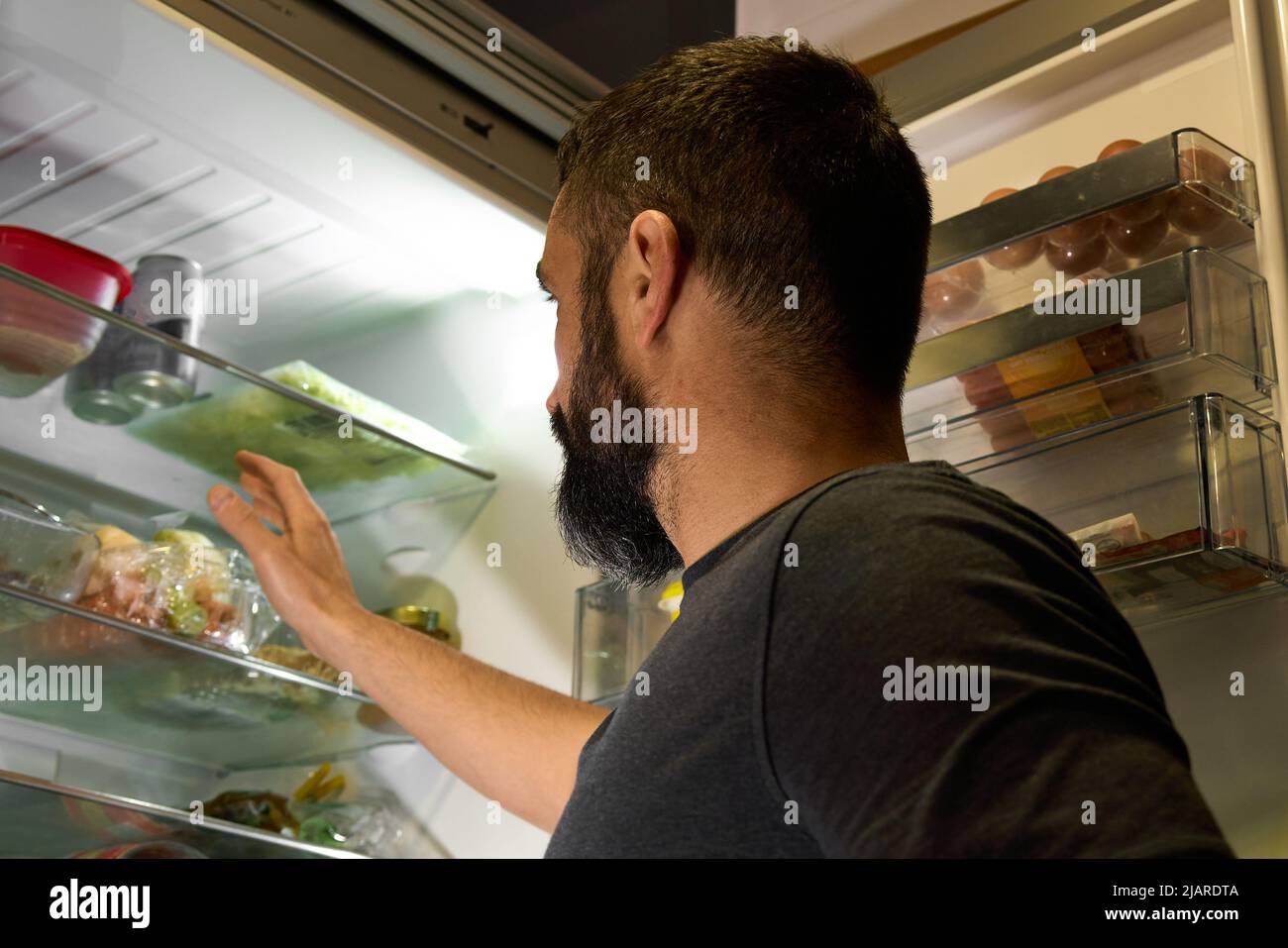 View from the back of a person opening the door of the fridge to catch ...