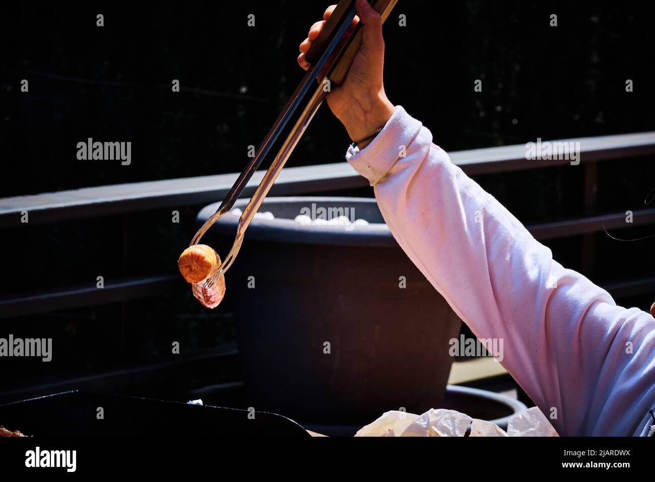 hand with a clamp placing the meat on a barbecue while cooking slowly ...