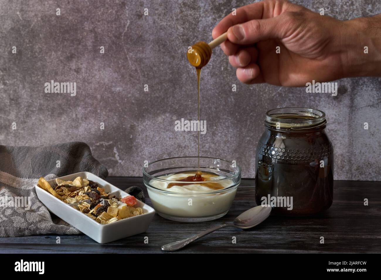 A person's hand pouring natural honey over freshly made homemade yogurt ...