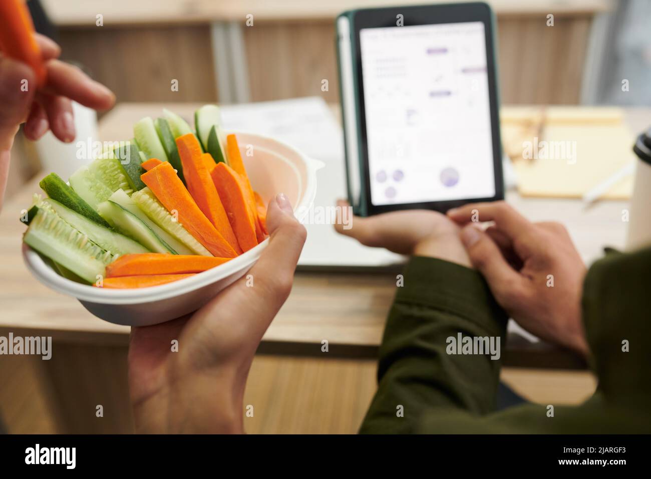 Businesswoman eating carrot and cucumber sticks when manager showing ...