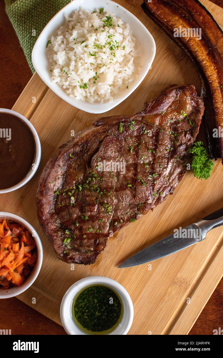Angus beef grill with 3 sides and rice sauce wood table with a knife ...
