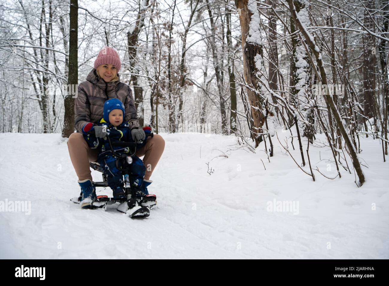 Mother with a child on a sled. A young woman with her little son rides ...