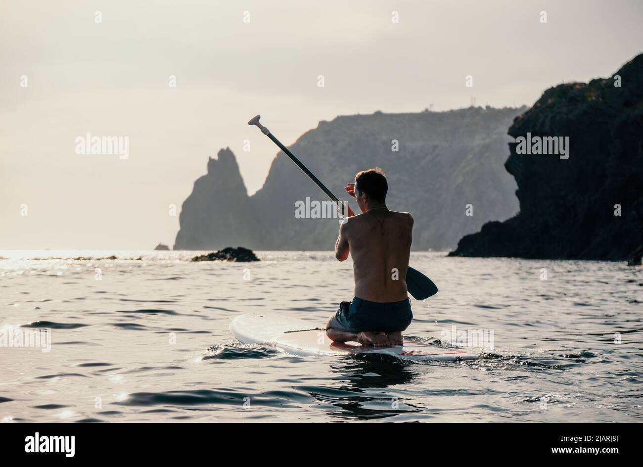 Side view foto of a man swiming and relaxing on the sup board. Sportive ...