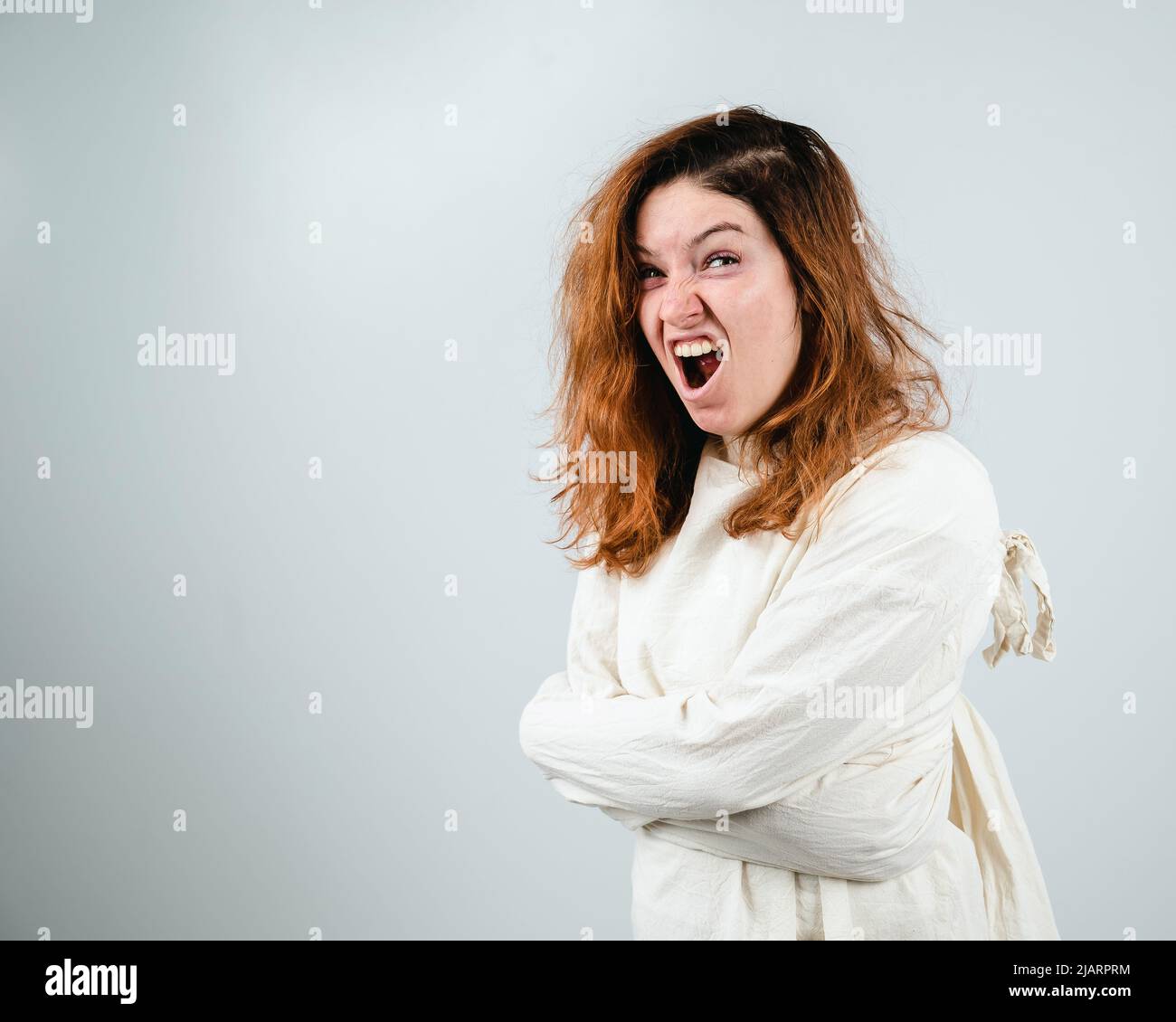 Close-up portrait of insane woman in straitjacket on white background ...