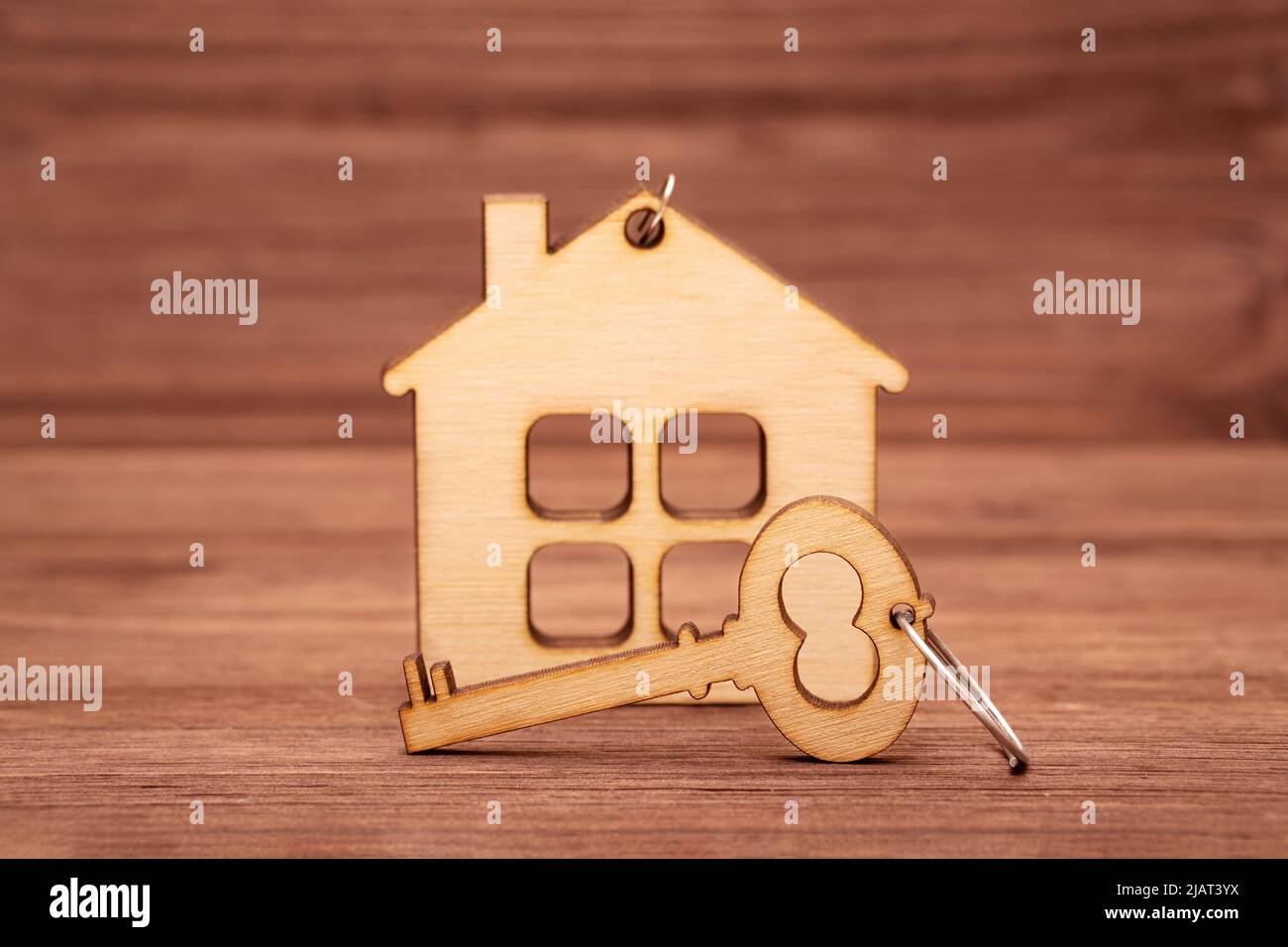 Wooden key with a wooden house shaped keychain on a wooden background ...