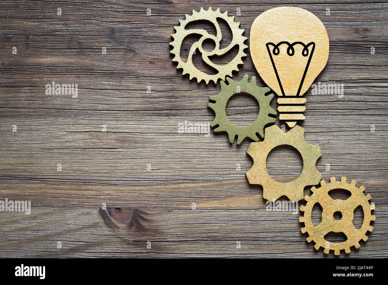Flat lightbulb shape, cogs and gears arranged on a wooden background. Creative thinking process ...