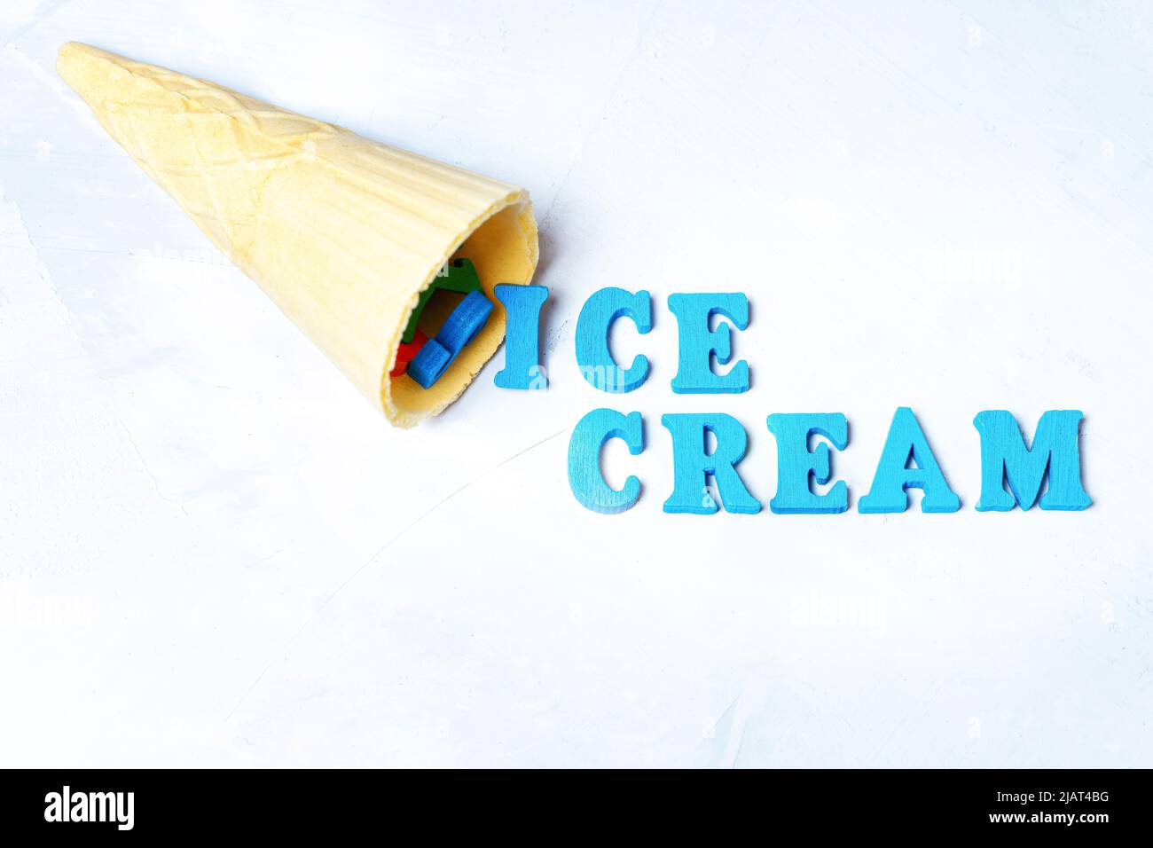 Text ICE CREAM and a waffle cone on a concrete background with copy ...