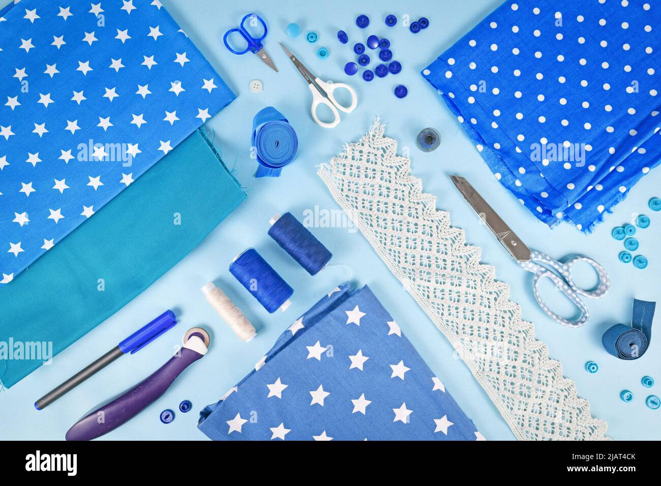 Sewing flat lay with various tools like fabric, scissors, spools and ...