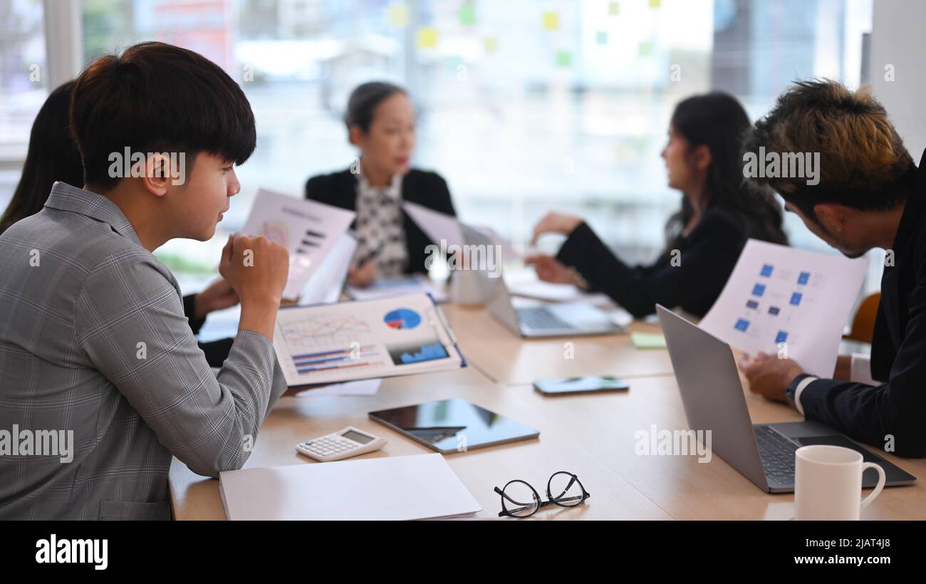 Concentrated diverse employees listening intently during discussion of ...