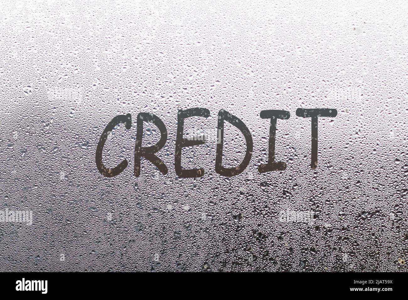the word credit written on night wet window glass close-up with blurred ...