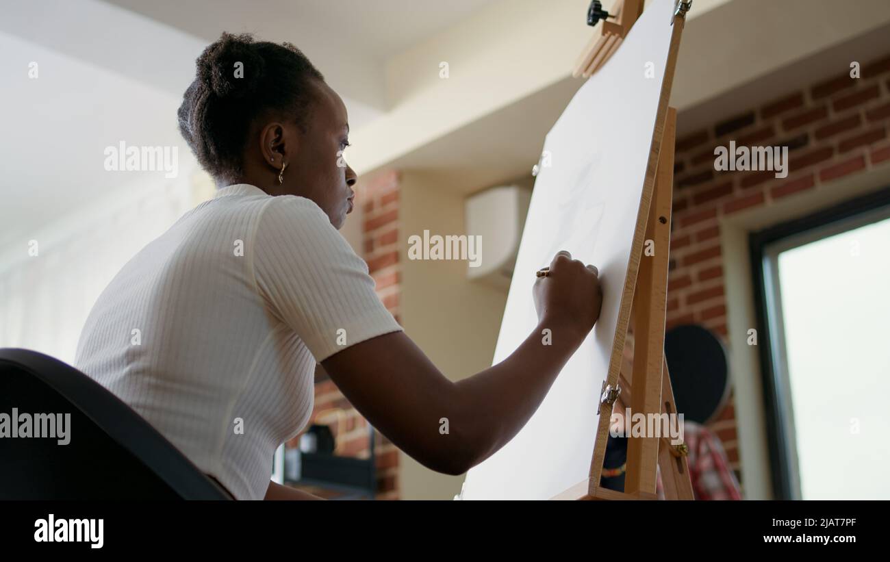 African american woman using pencil to draw vase sketch on canvas ...