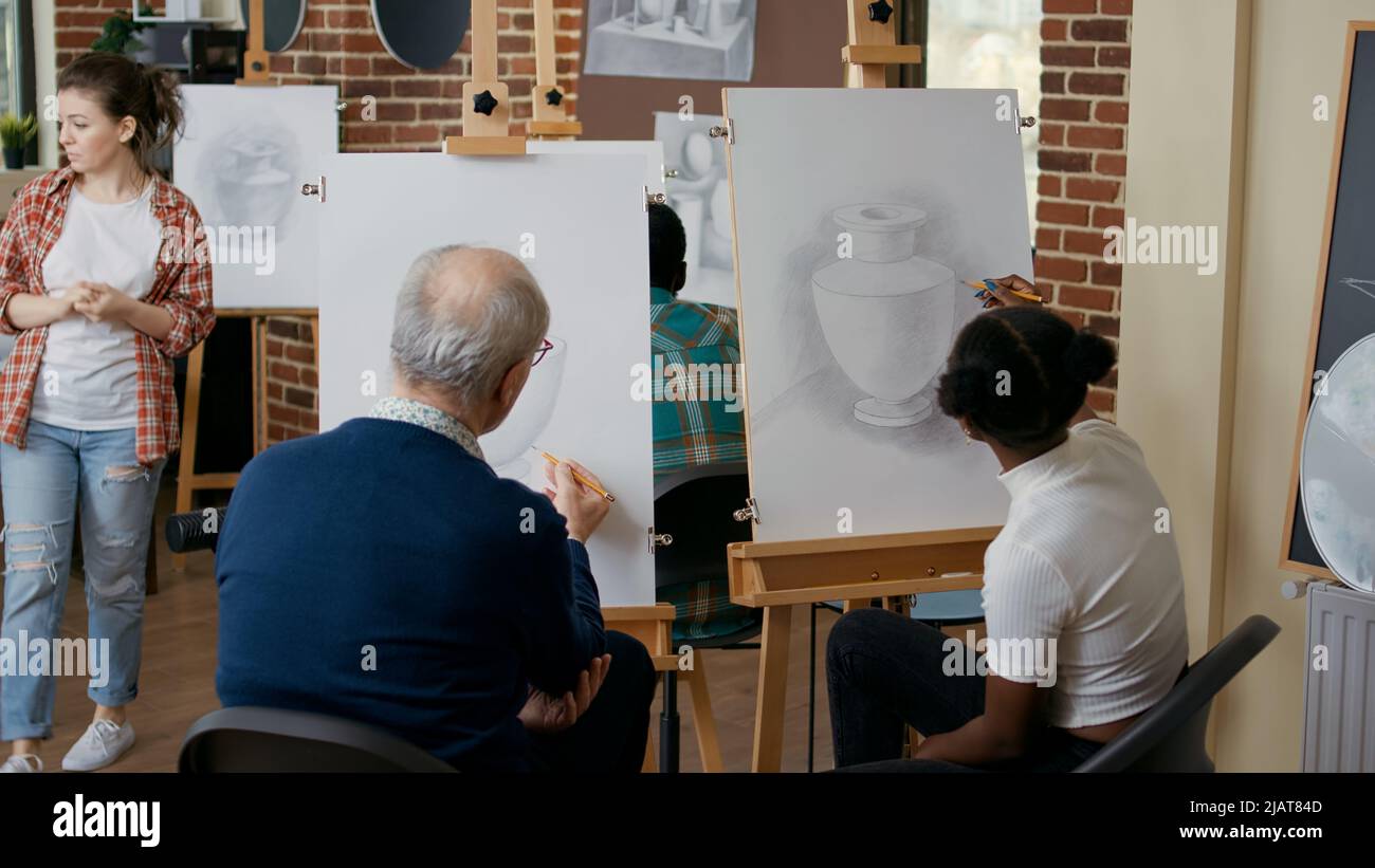 Multi ethnic team of people learning drawing technique together in art ...