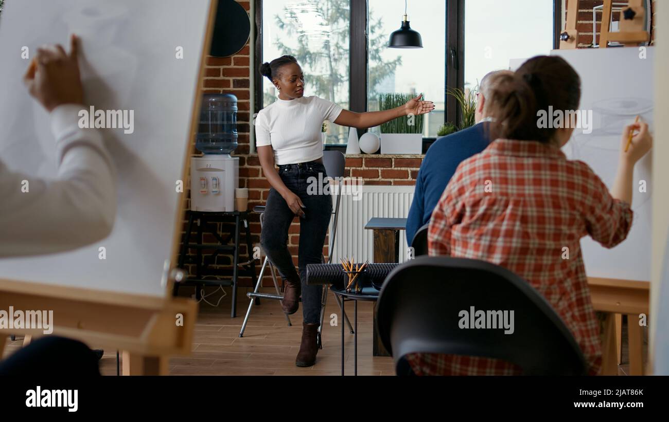 Young teacher explaining drawing skills to students in art class ...