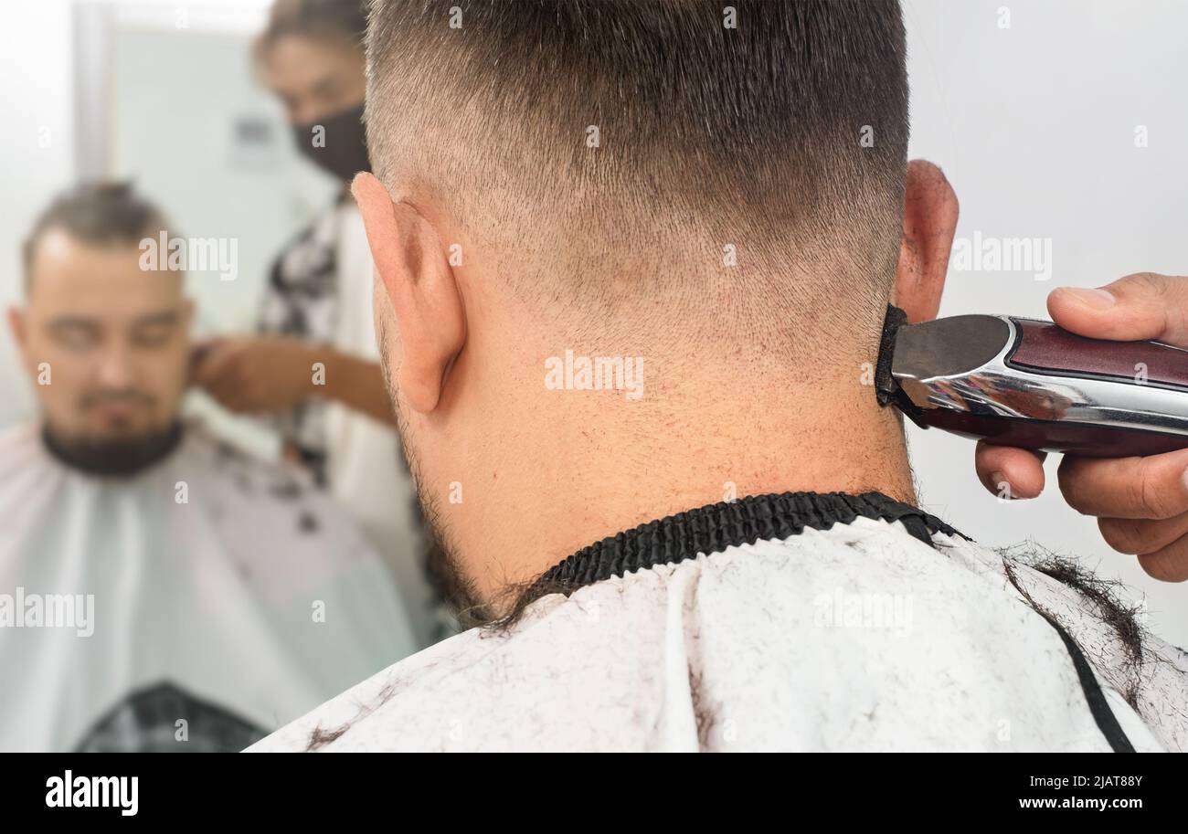 Barber cutting a man's hair with a razor in a barbershop Stock Photo ...