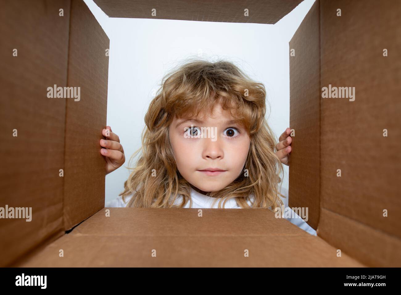 The surprised child unpacking, opening carton box and looking inside ...