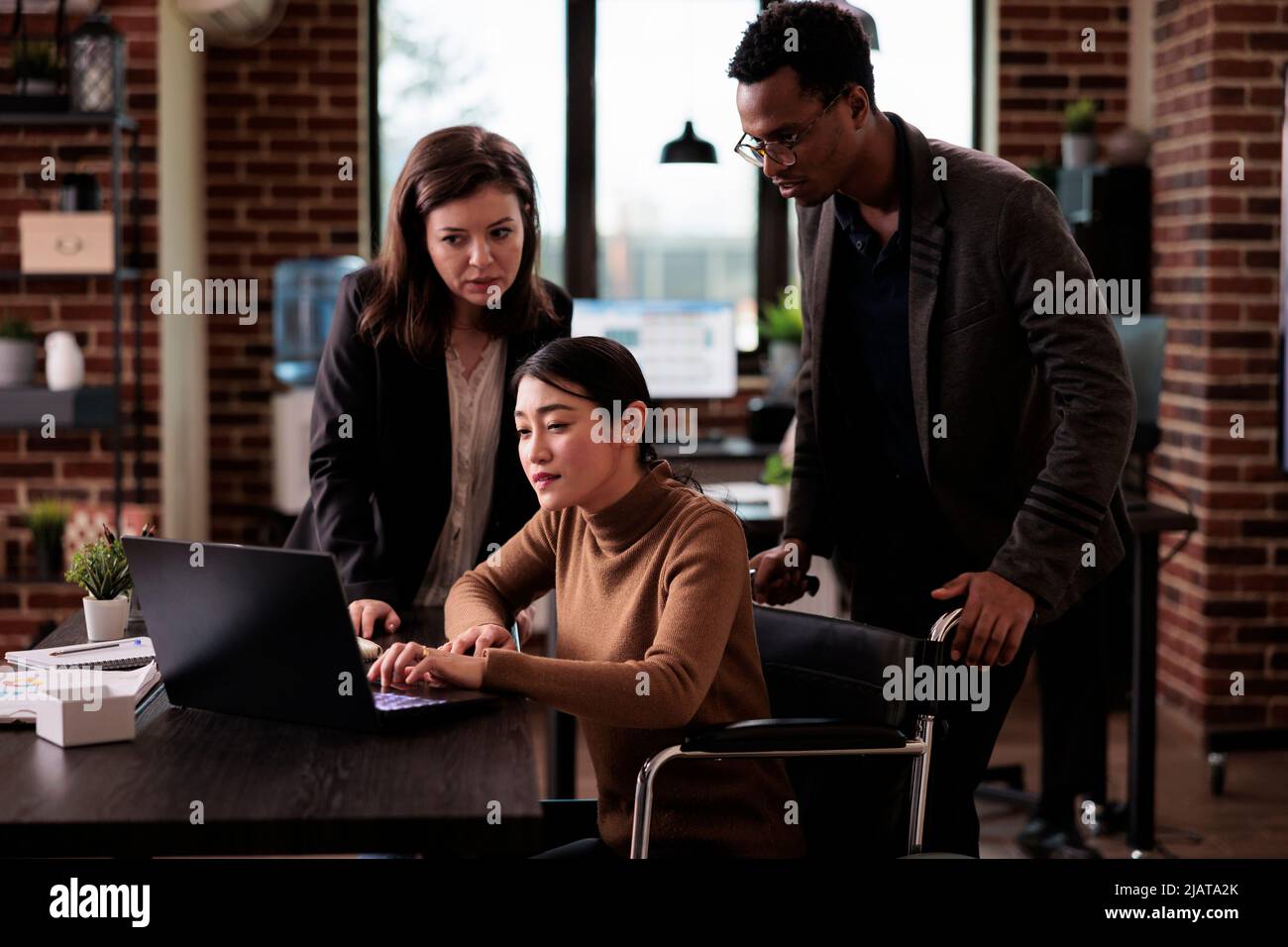Diverse team of colleagues working with paralyzed employee sitting in ...