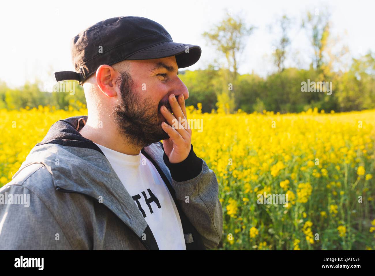 Man holding back laughter with his hand covering his mouth. Positive ...