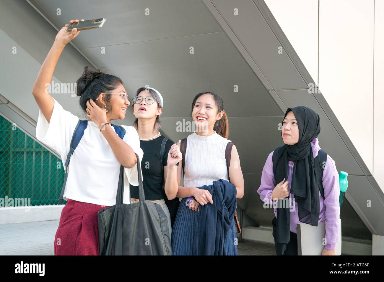 Group of young college multi-racial women students having fun, laughing and taking selfie ...