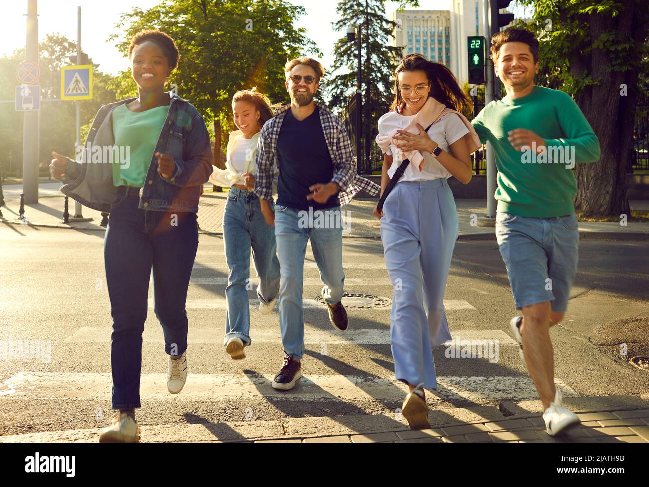 Group of happy diverse friends run as they cross the street during an ...