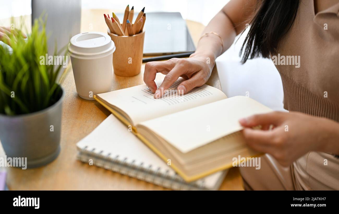 Relaxed woman reading a novel in her home workplace. Female researching ...